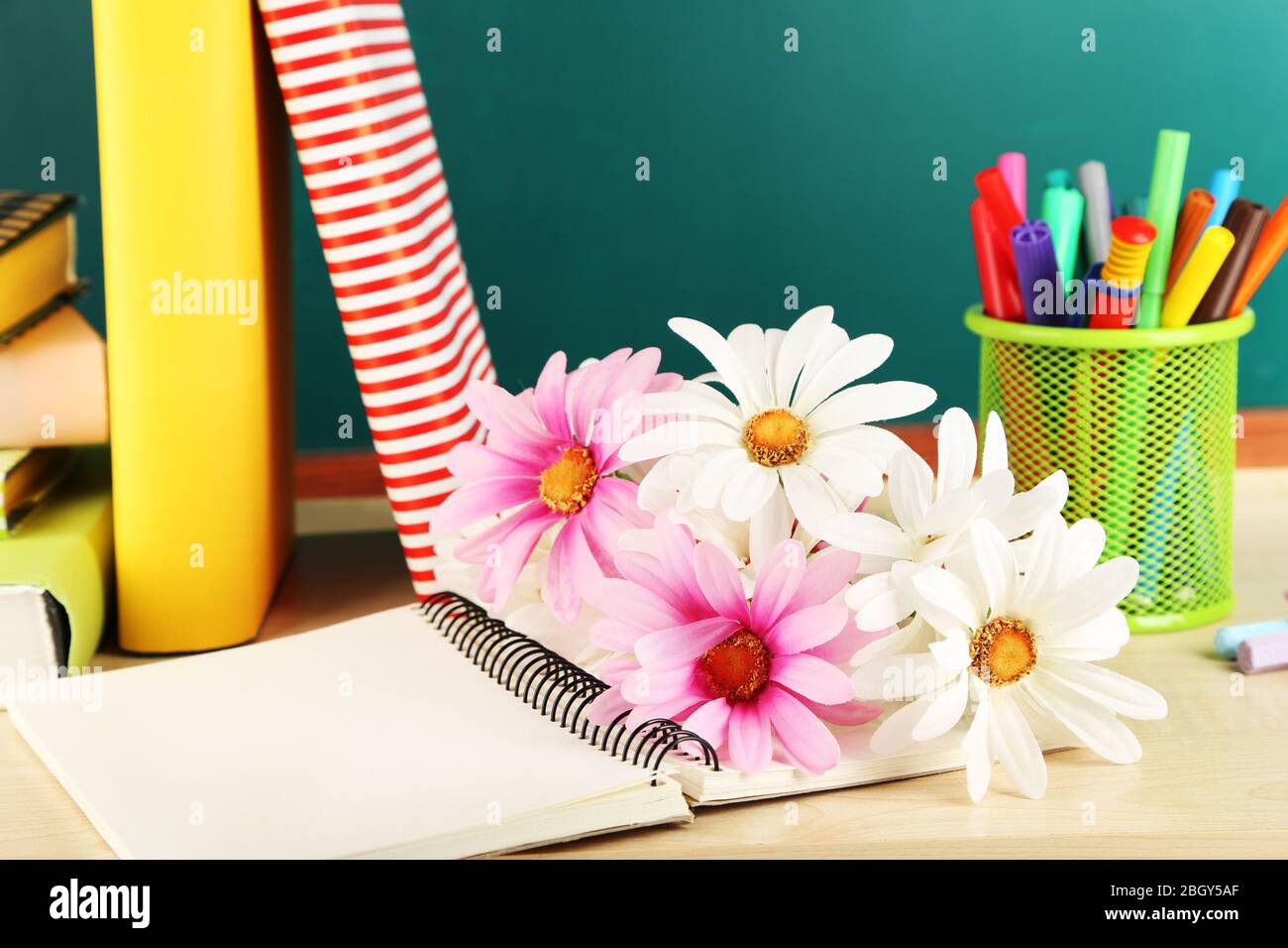 Composition on desk with books and flowers on green blackboard ...