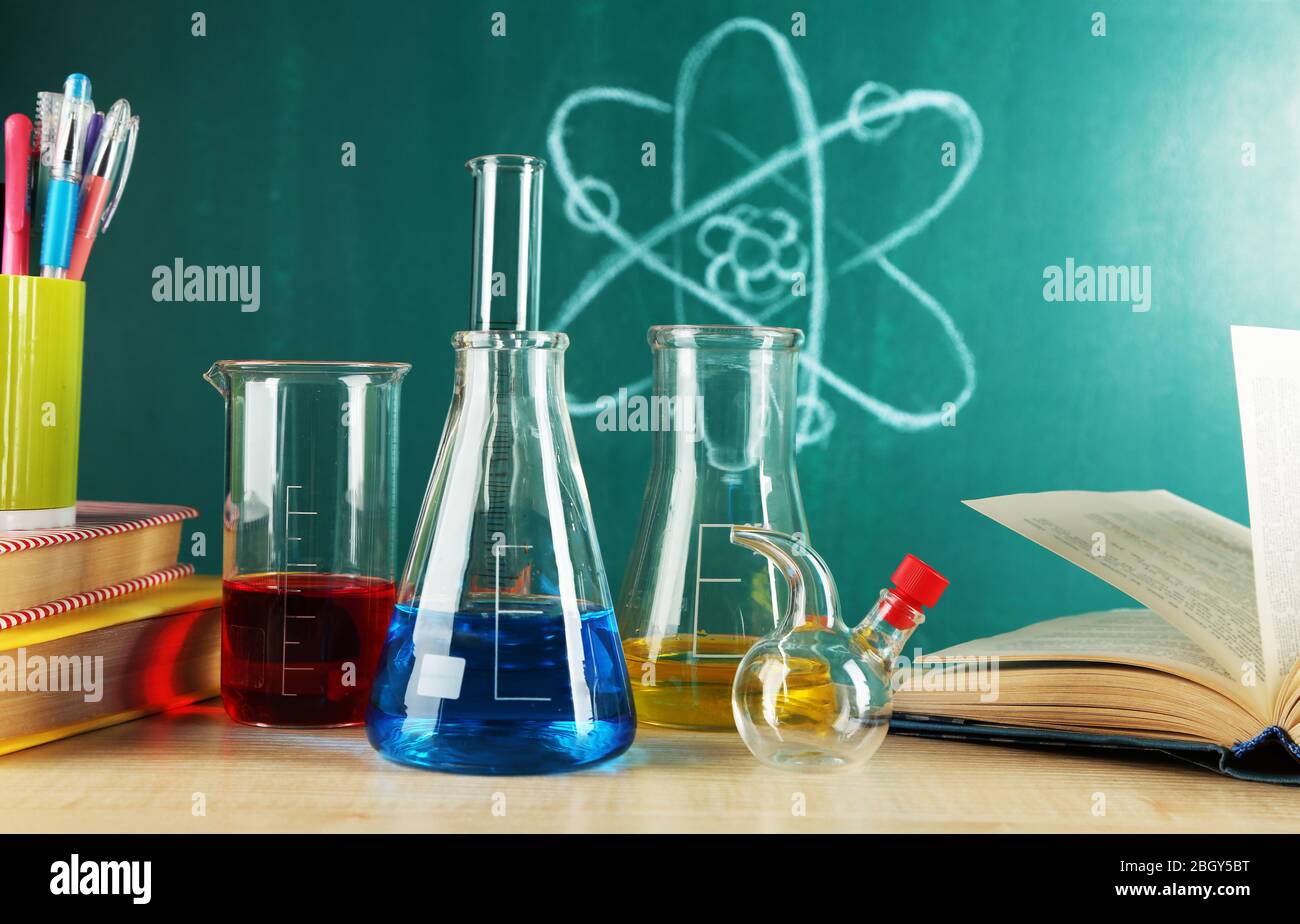 Desk in chemistry class with test tubes on green blackboard background ...