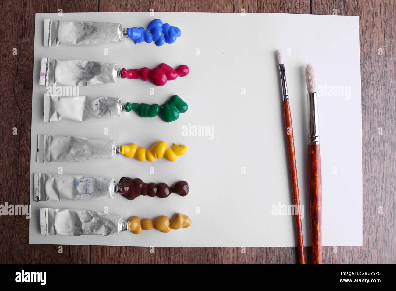 Colorful paint tubes squeezed with brush on white sheet of paper and ...