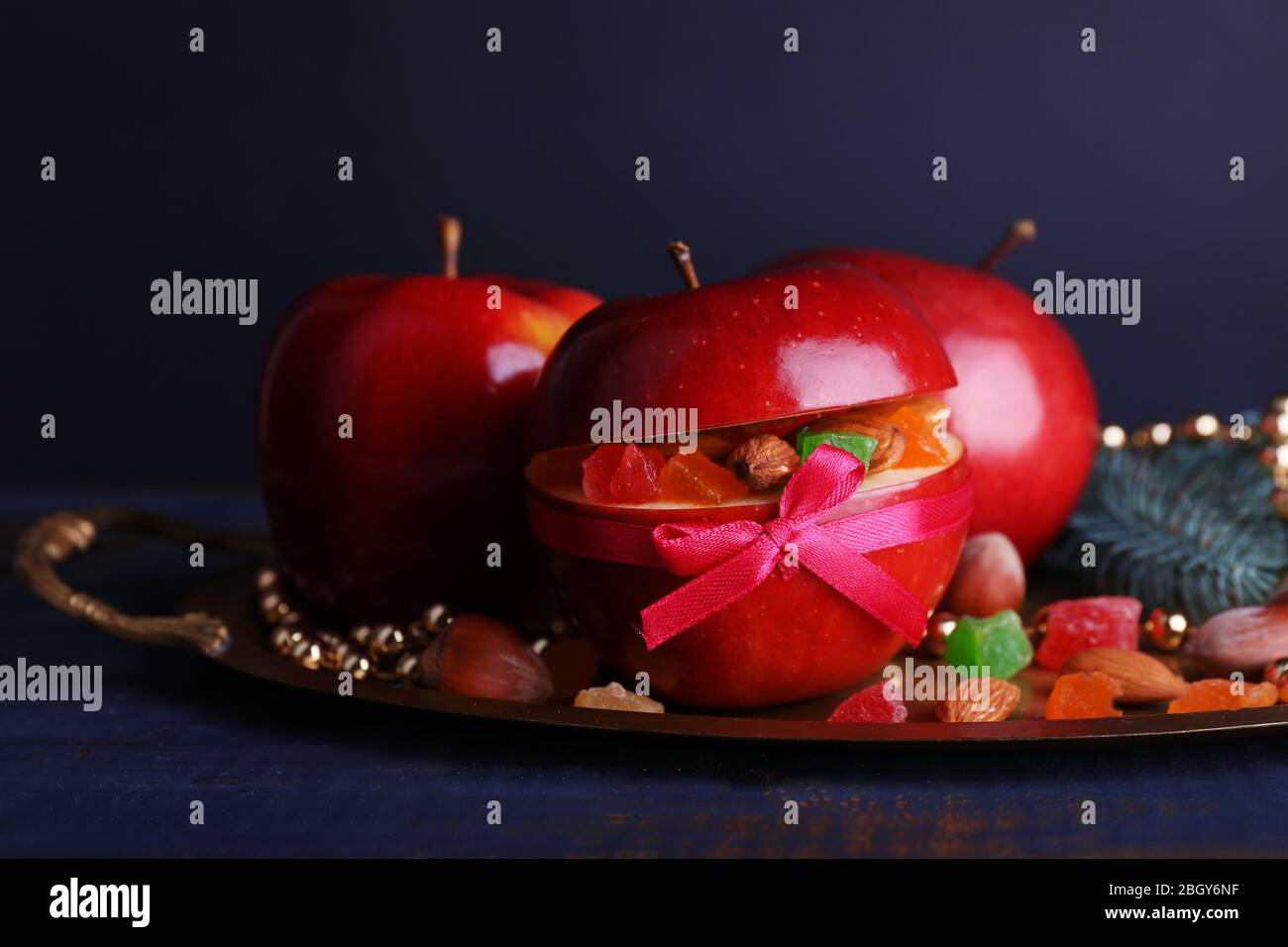 Red apples stuffed with dried fruits on metal tray on color wooden ...