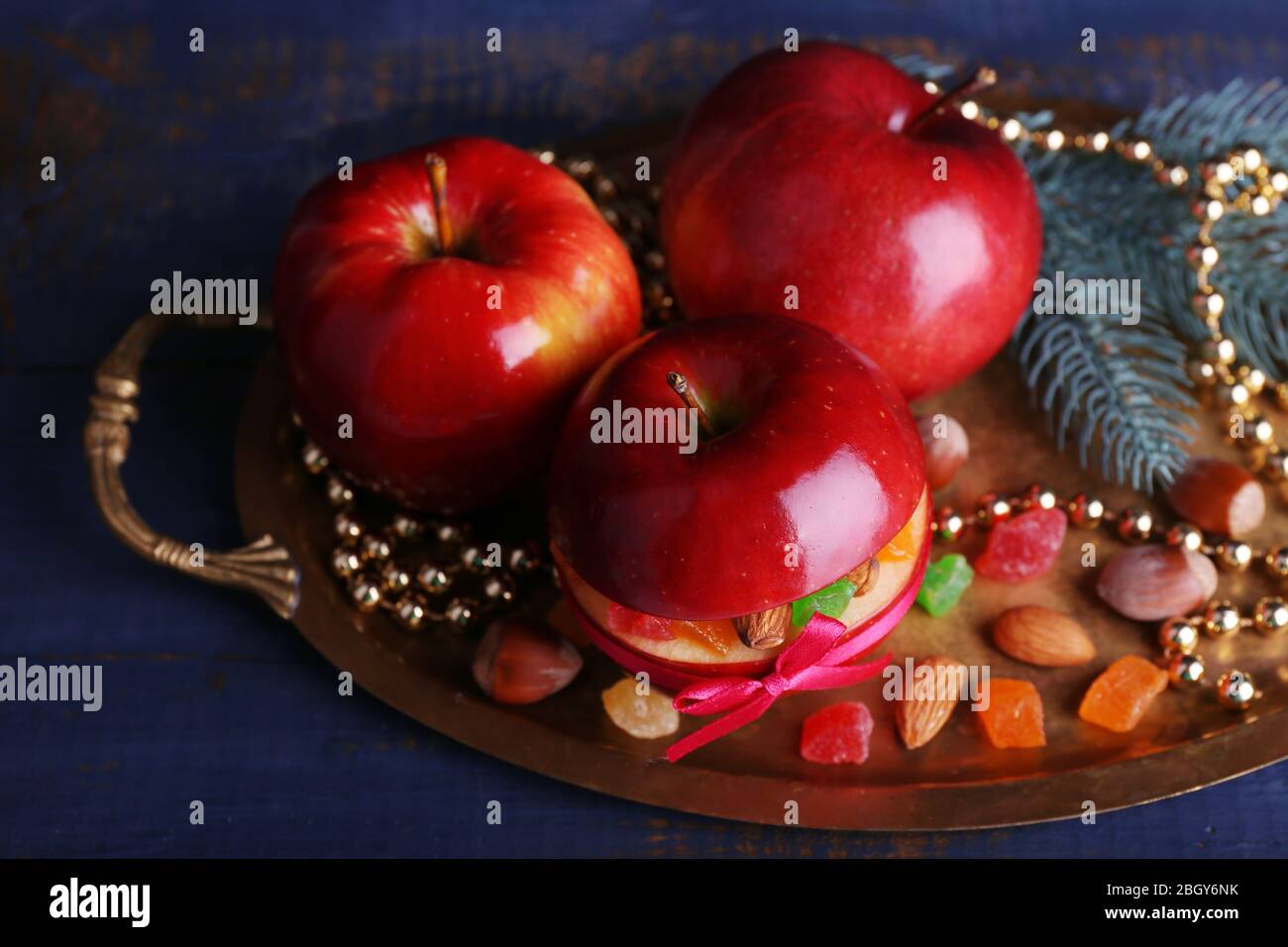 Christmas red apples stuffed with dried fruits on metal tray on color ...