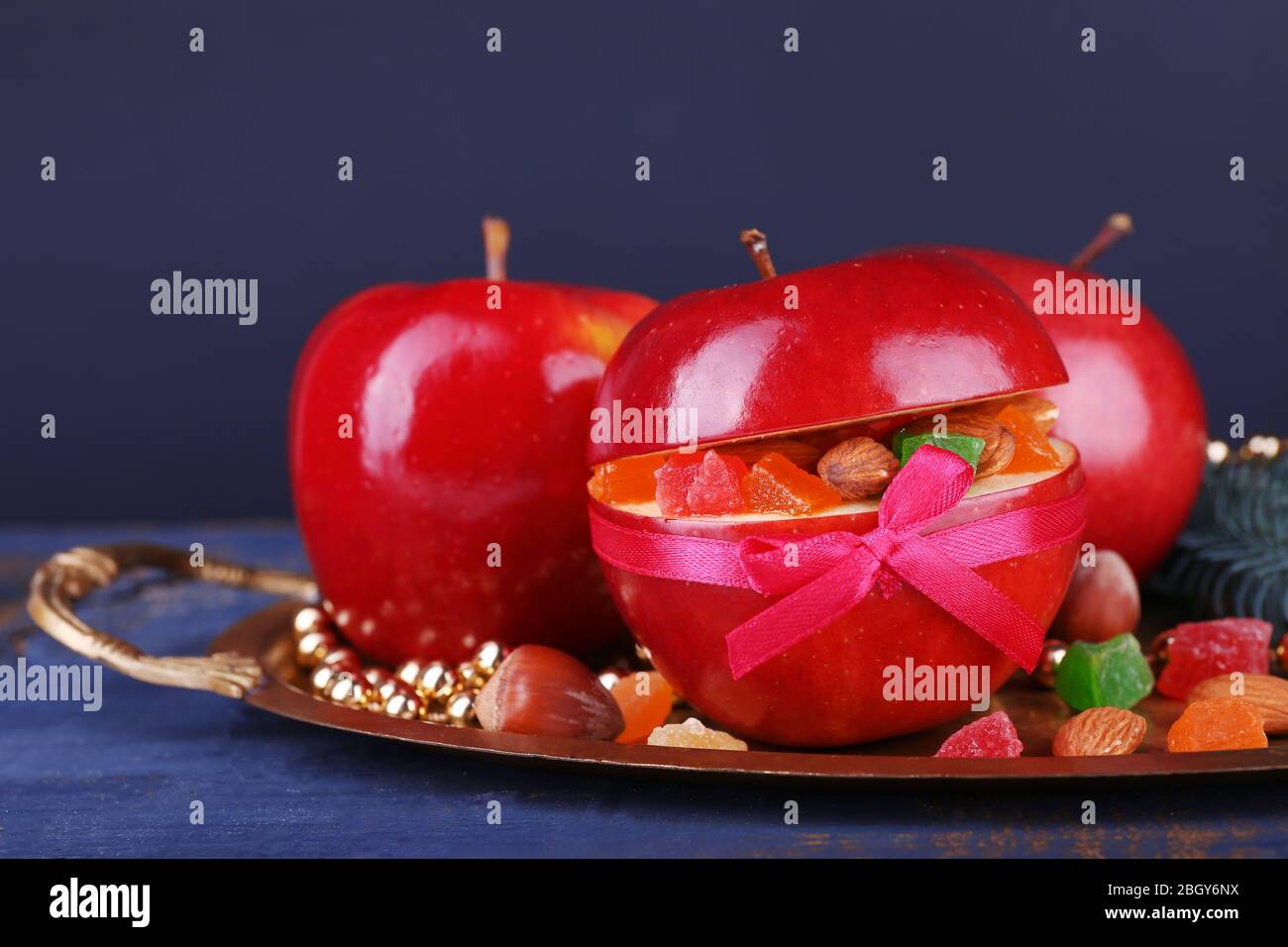 Christmas red apples stuffed with dried fruits on metal tray on color ...