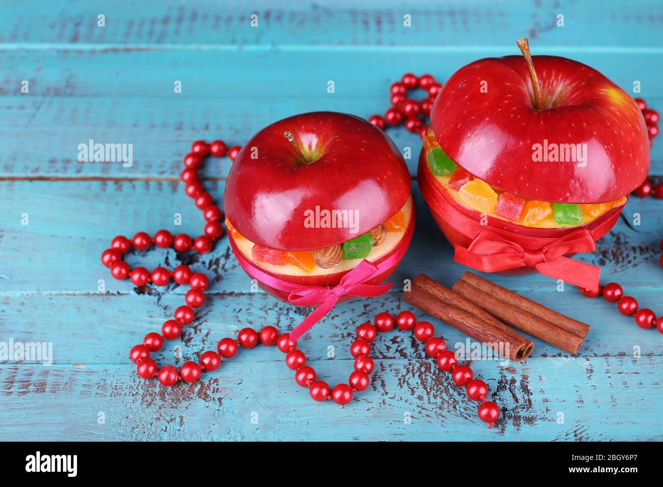 Christmas red apples stuffed with dried fruits on color wooden table ...
