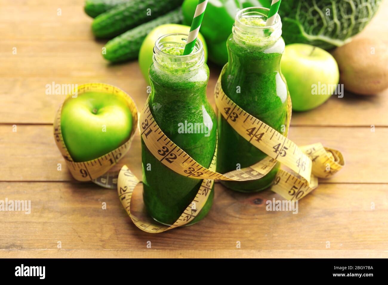 Green fresh healthy juice in glass bottles with fruits and vegetables ...