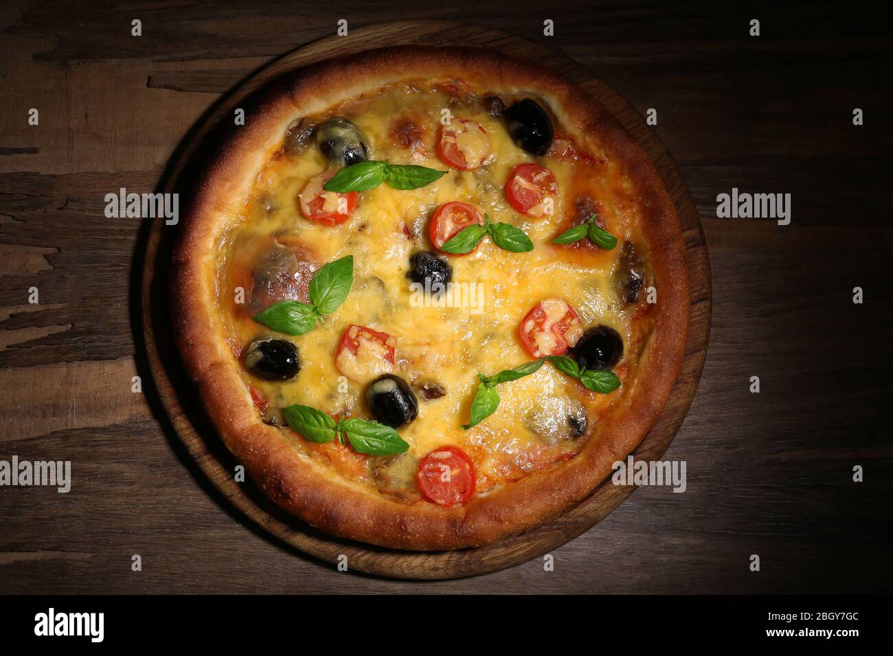 Pizza on board and wooden table background Stock Photo - Alamy