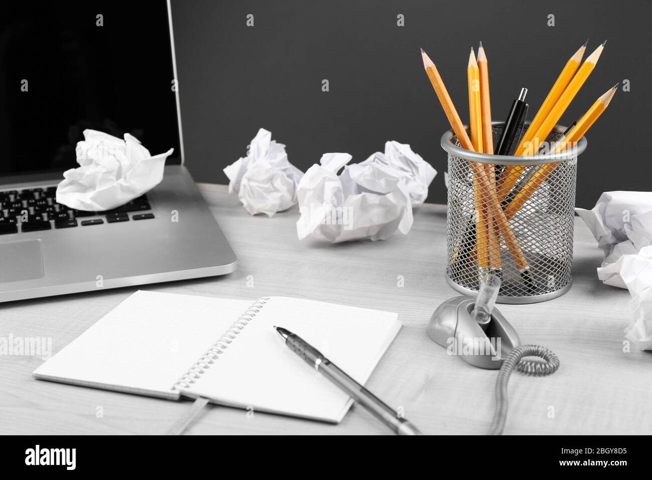 Working mess with crumpled paper and notebook on wooden table and dark ...