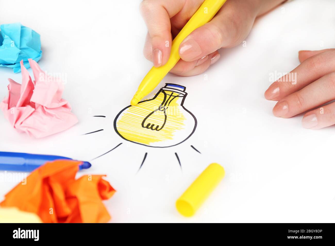 Female hand drawing symbol of idea as light bulb on sheet of paper, on ...