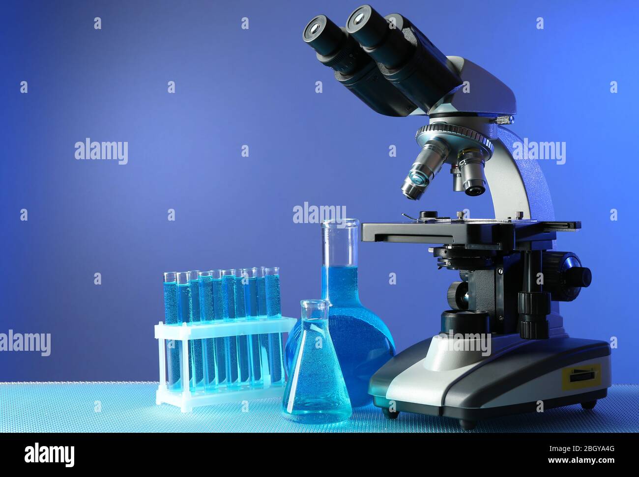 Microscope and test tubes on table, on color background Stock Photo - Alamy