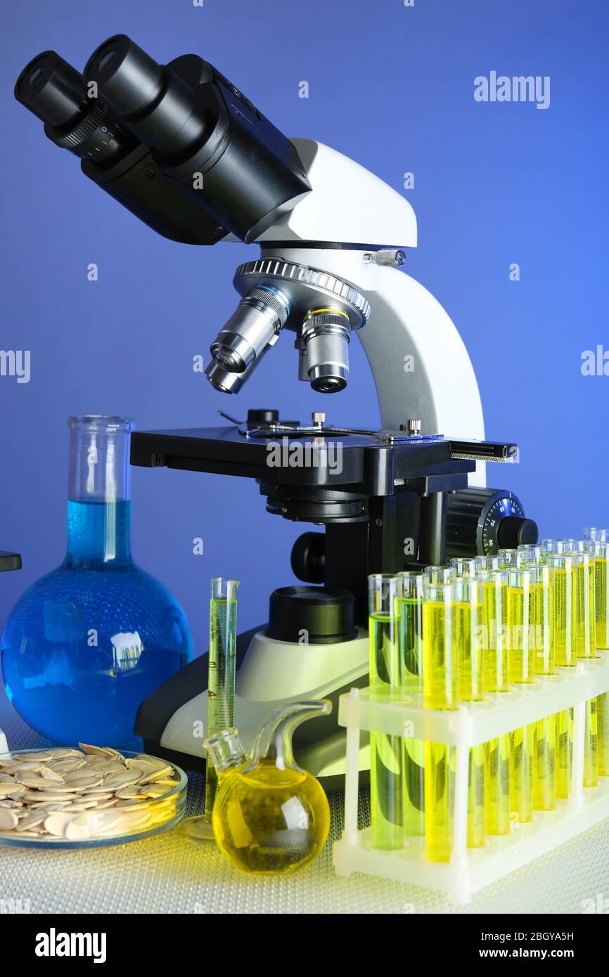 Microscope, grains and test tubes on table, on color background Stock ...