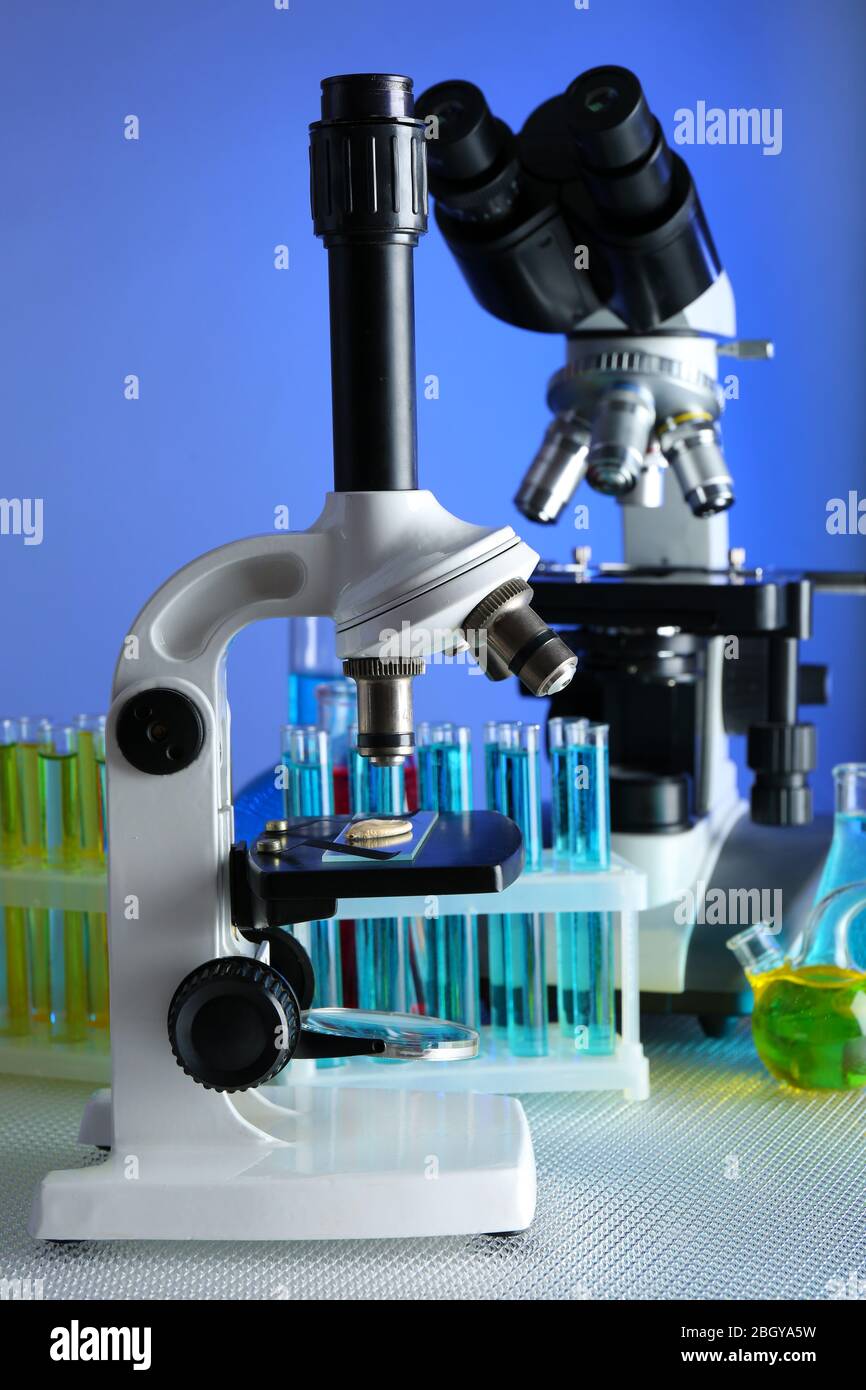 Microscopes and test tubes on table, on color background Stock Photo ...