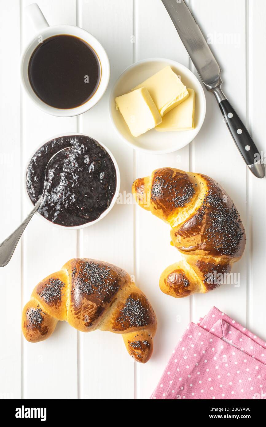 Sweet homemade croissants with poppy, jam and butter on white table ...