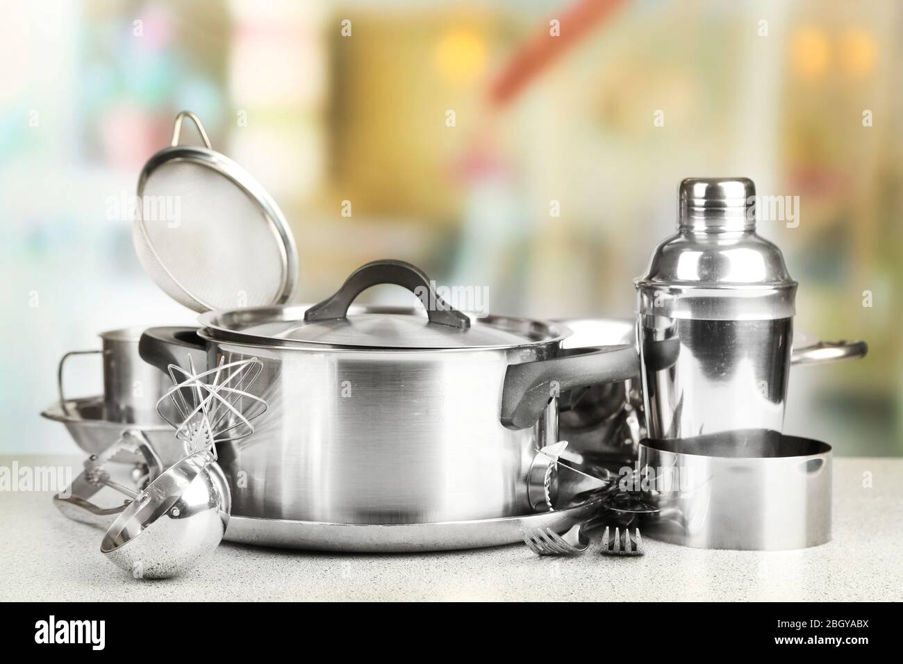 Stainless steel kitchenware on table, on light background Stock Photo ...