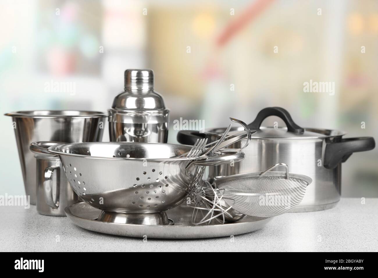 Stainless steel kitchenware on table, on light background Stock Photo ...