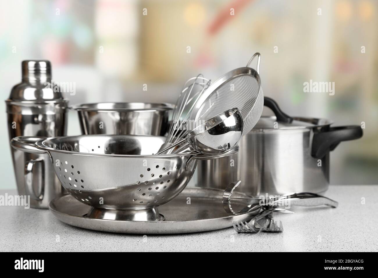 Stainless steel kitchenware on table, on light background Stock Photo ...