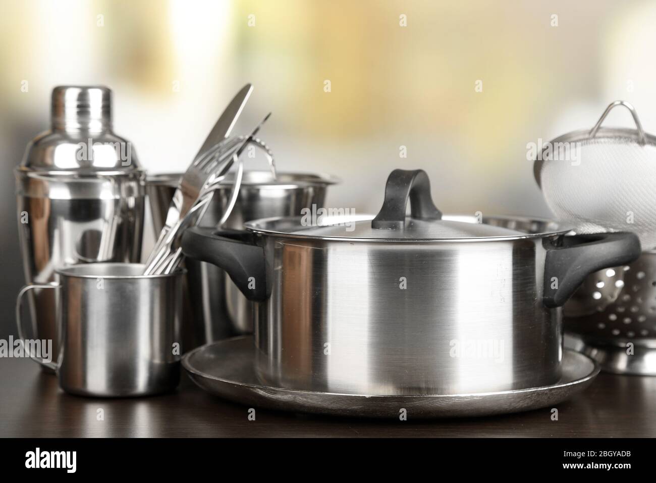 Stainless steel kitchenware on table, on light background Stock Photo ...