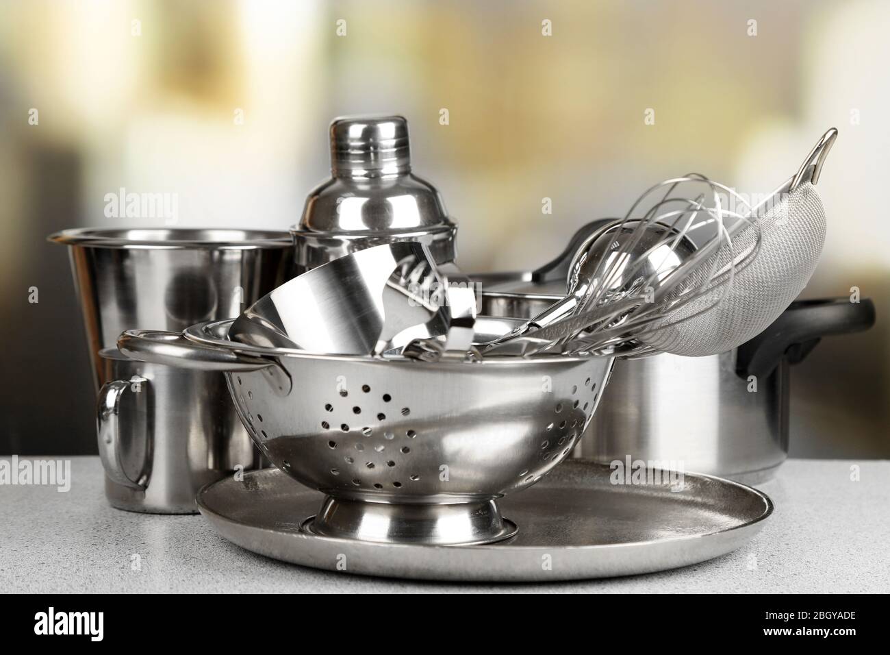 Stainless steel kitchenware on table, on light background Stock Photo ...