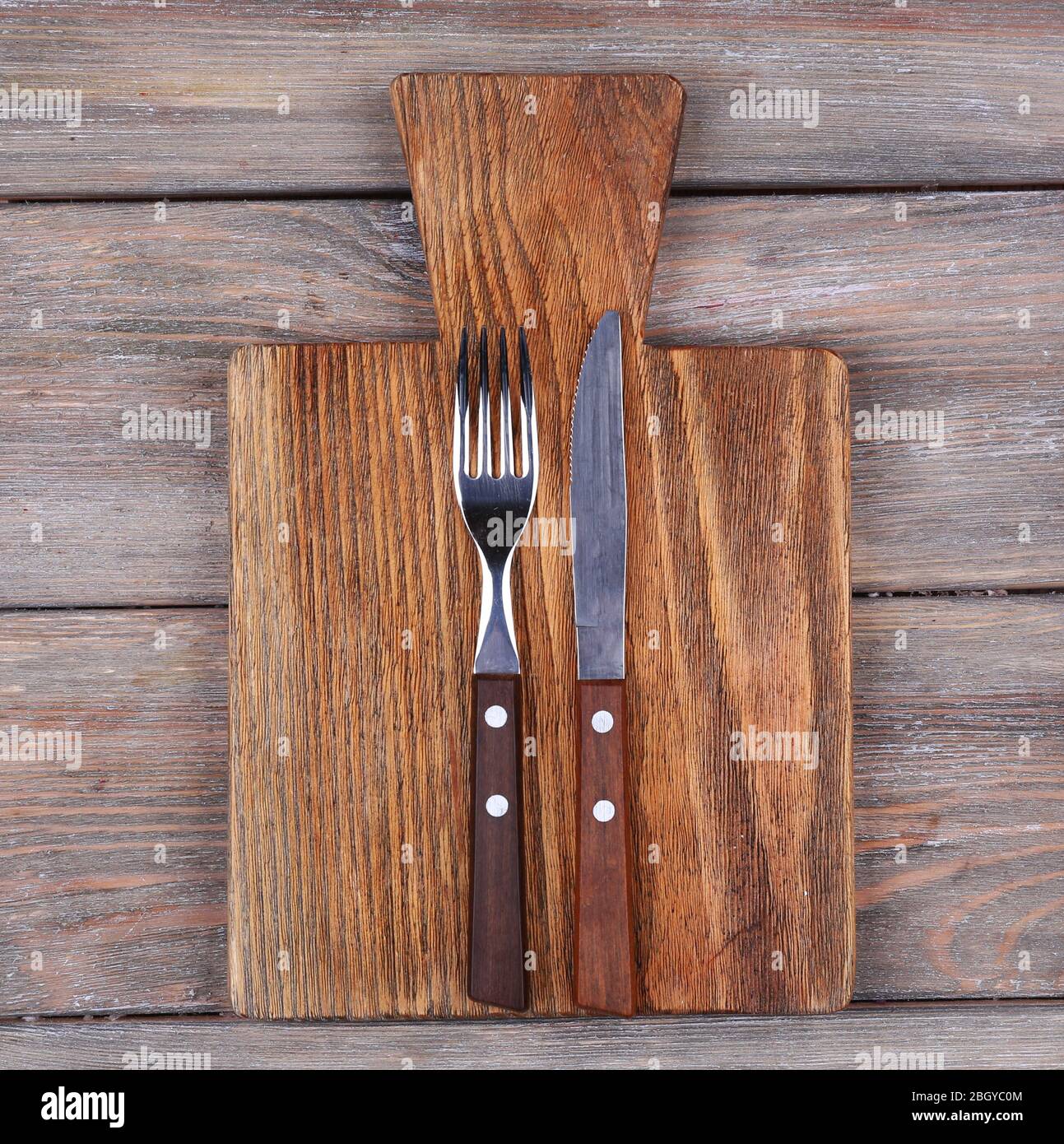 Cutting board with fork and knife on rustic wooden planks background ...