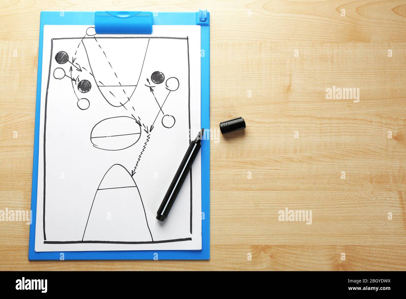 Scheme basketball game on clip board paper with marker and wooden table ...