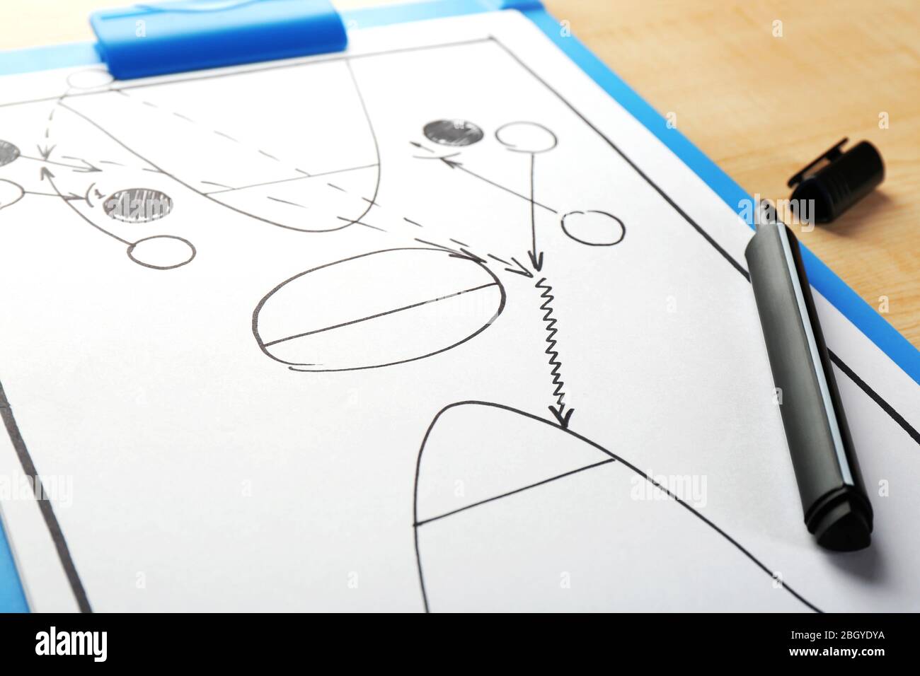 Scheme basketball game on clip board paper with marker and wooden table ...