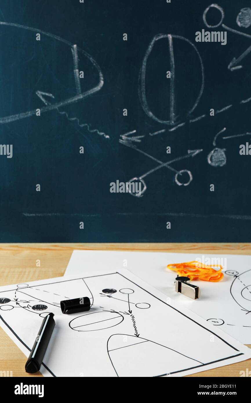 Table with sheets of paper and blackboard with scheme basketball game ...