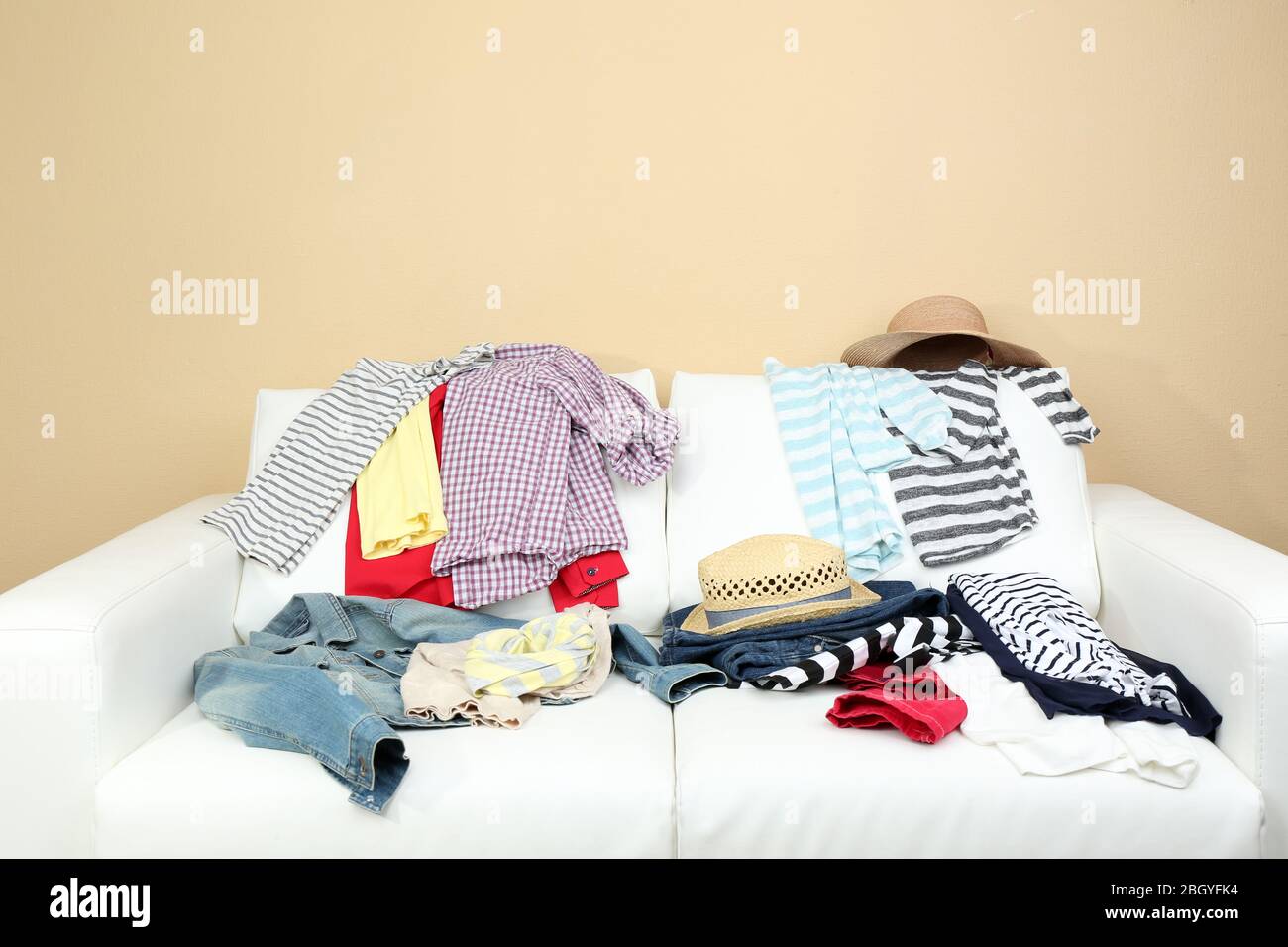 Messy clothing on white sofa, on light wall background Stock Photo - Alamy