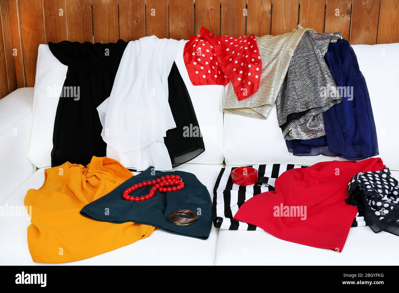 Messy clothing on white sofa, on wooden planks background Stock Photo ...