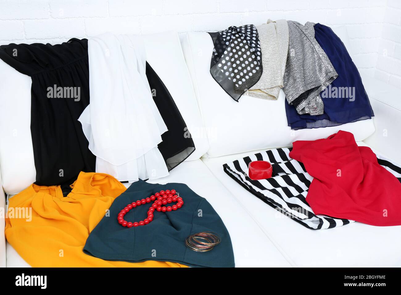 Messy clothing on white sofa, on brick wall background Stock Photo - Alamy