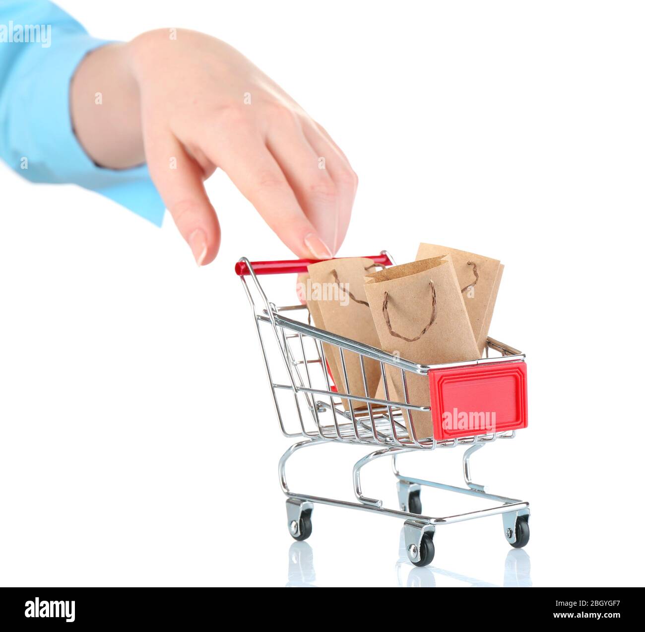 Female hand pushing small shopping cart with bags, isolated on white ...