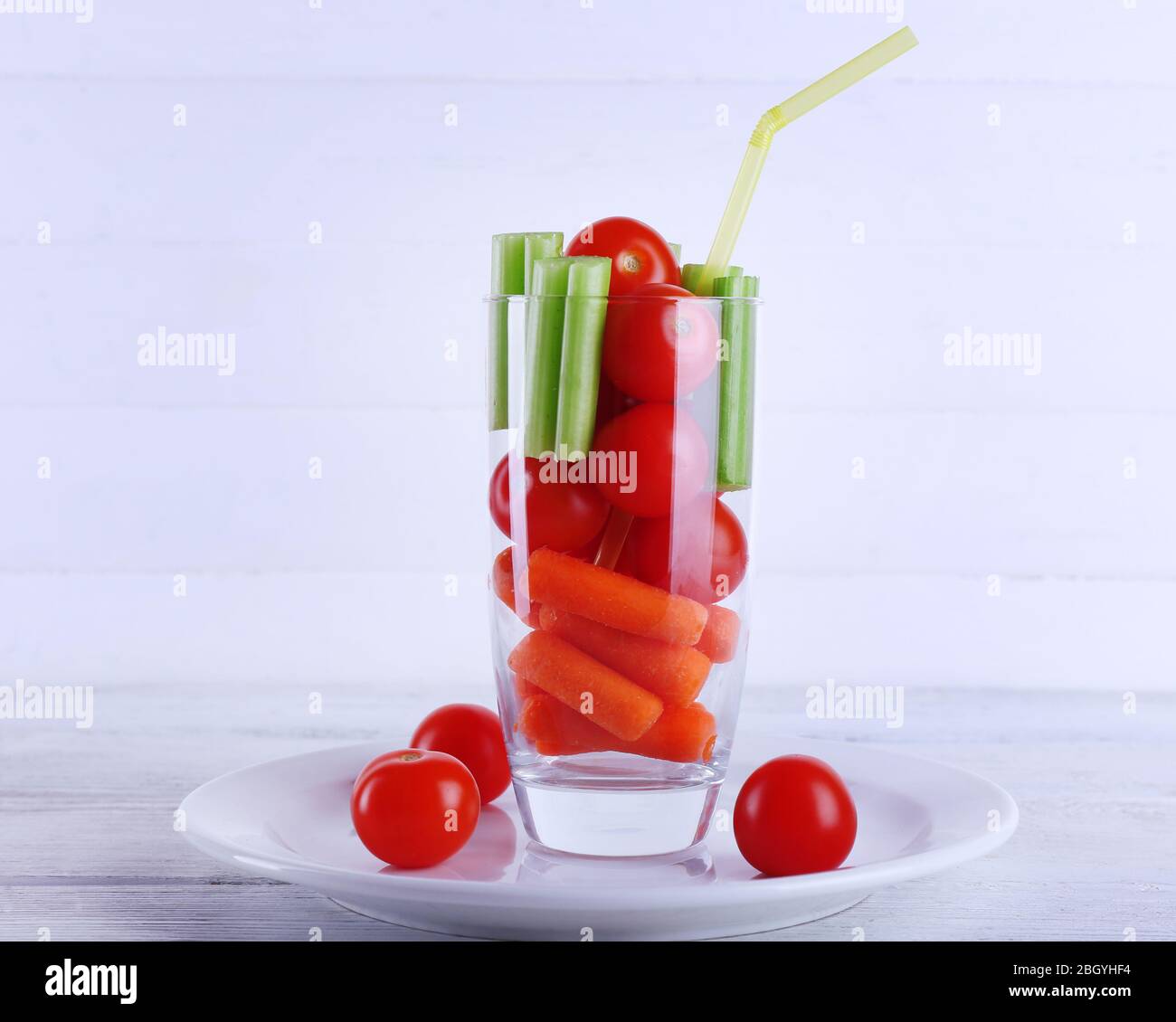 Vegetables in glass with tube on plate and color wooden planks ...
