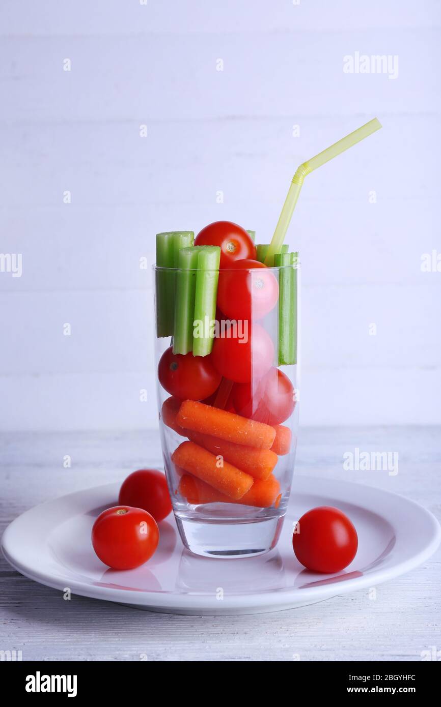 Vegetables in glass with tube on plate and color wooden planks ...