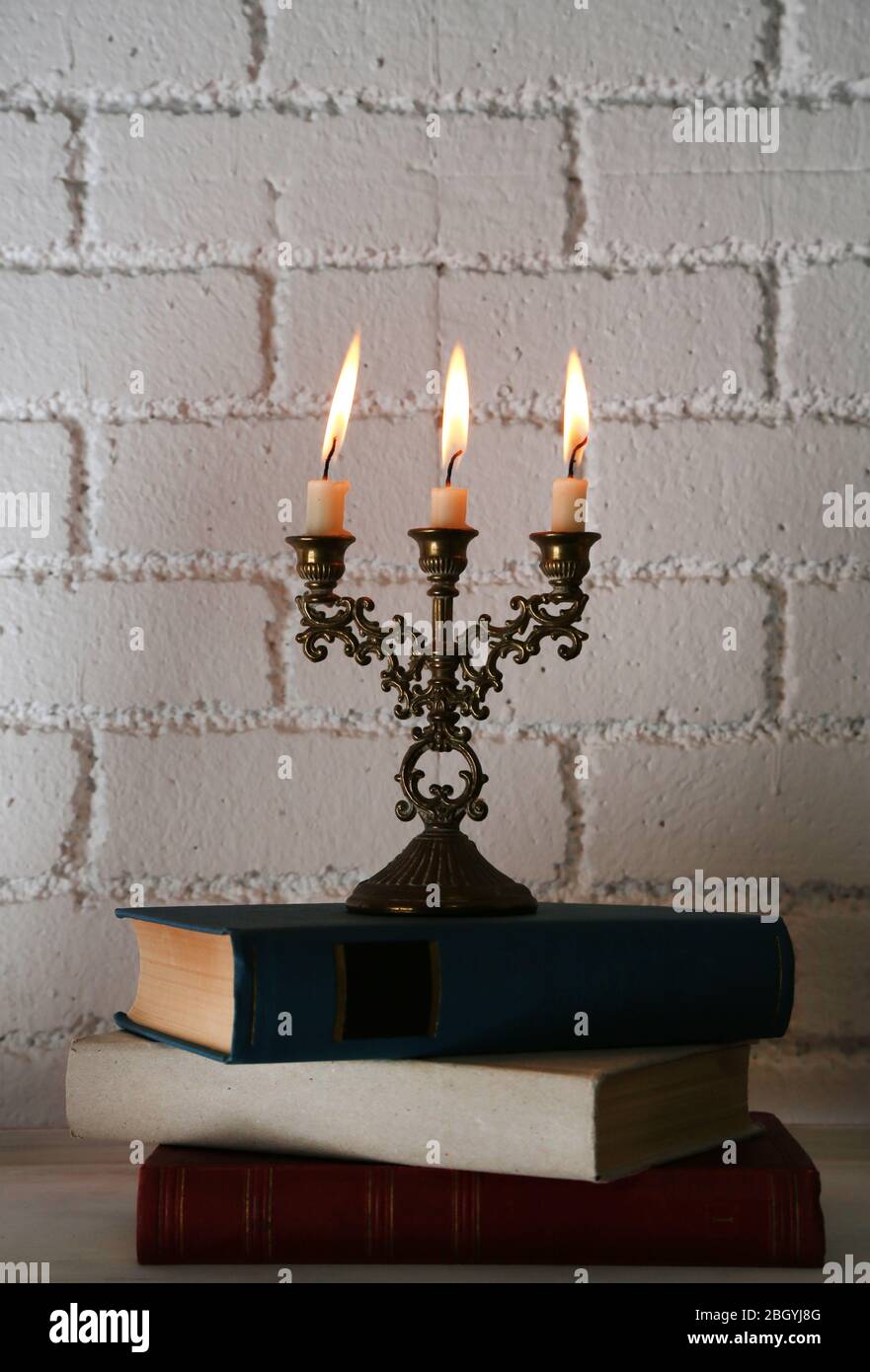 Bookshelf with books and candlestick on brick wall background Stock ...