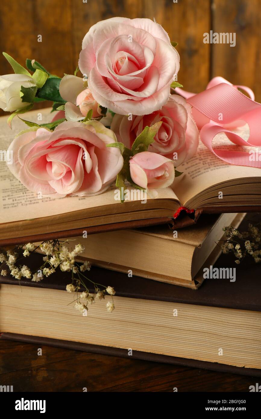 Books with flowers on wooden background Stock Photo - Alamy