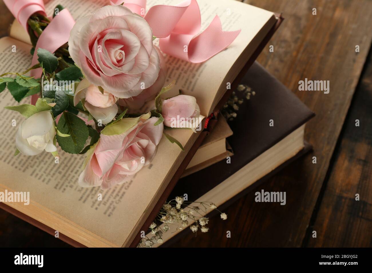Books with flowers on wooden background Stock Photo - Alamy