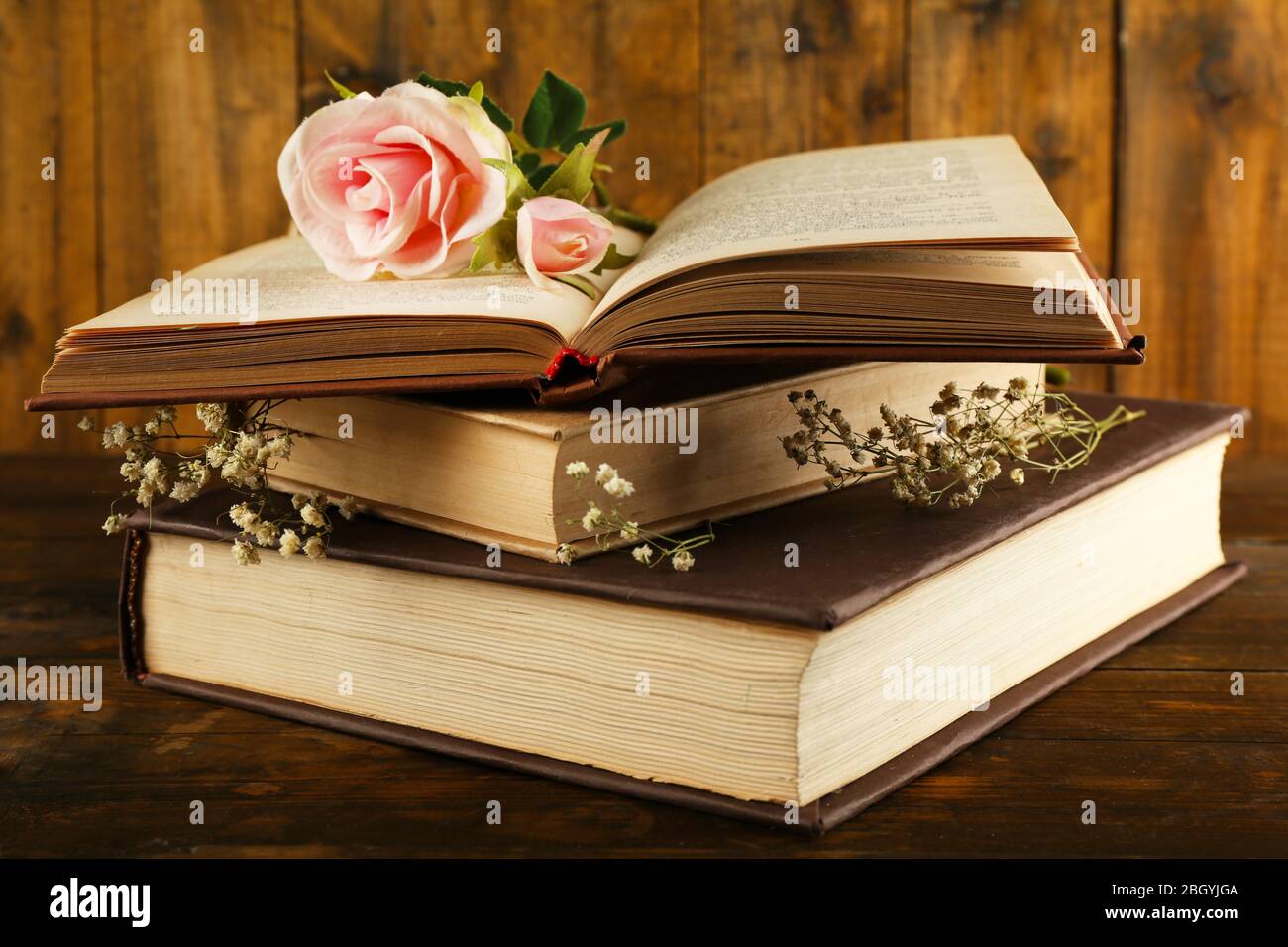 Books with flowers on wooden background Stock Photo - Alamy
