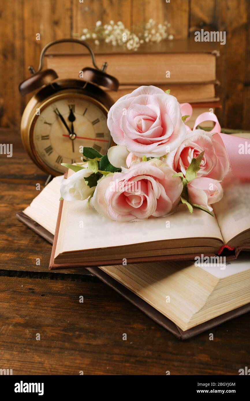 Books with flowers and clock on wooden background Stock Photo - Alamy