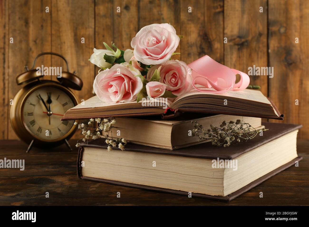 Books with flowers and clock on wooden background Stock Photo - Alamy