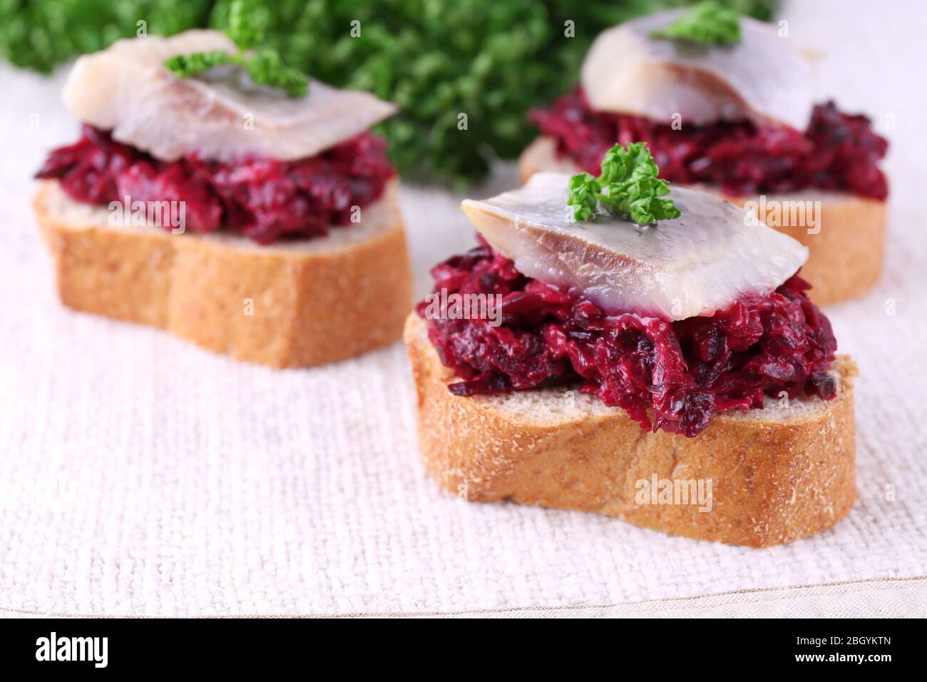 Rye toasts with herring and beets on tablecloth background Stock Photo ...