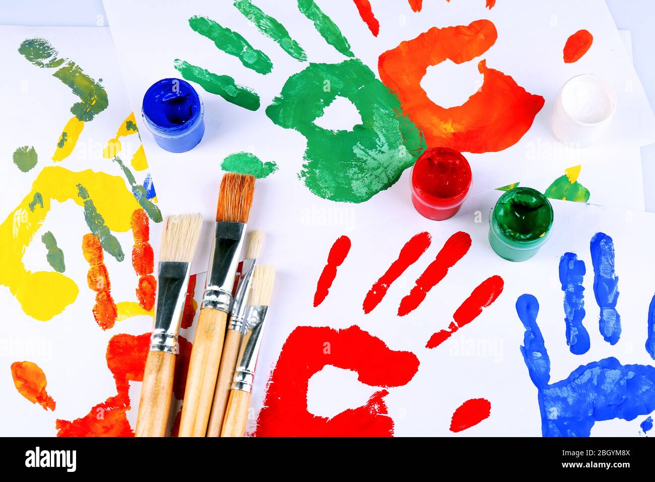 Hand prints of paint, paints and brushes on white background Stock ...