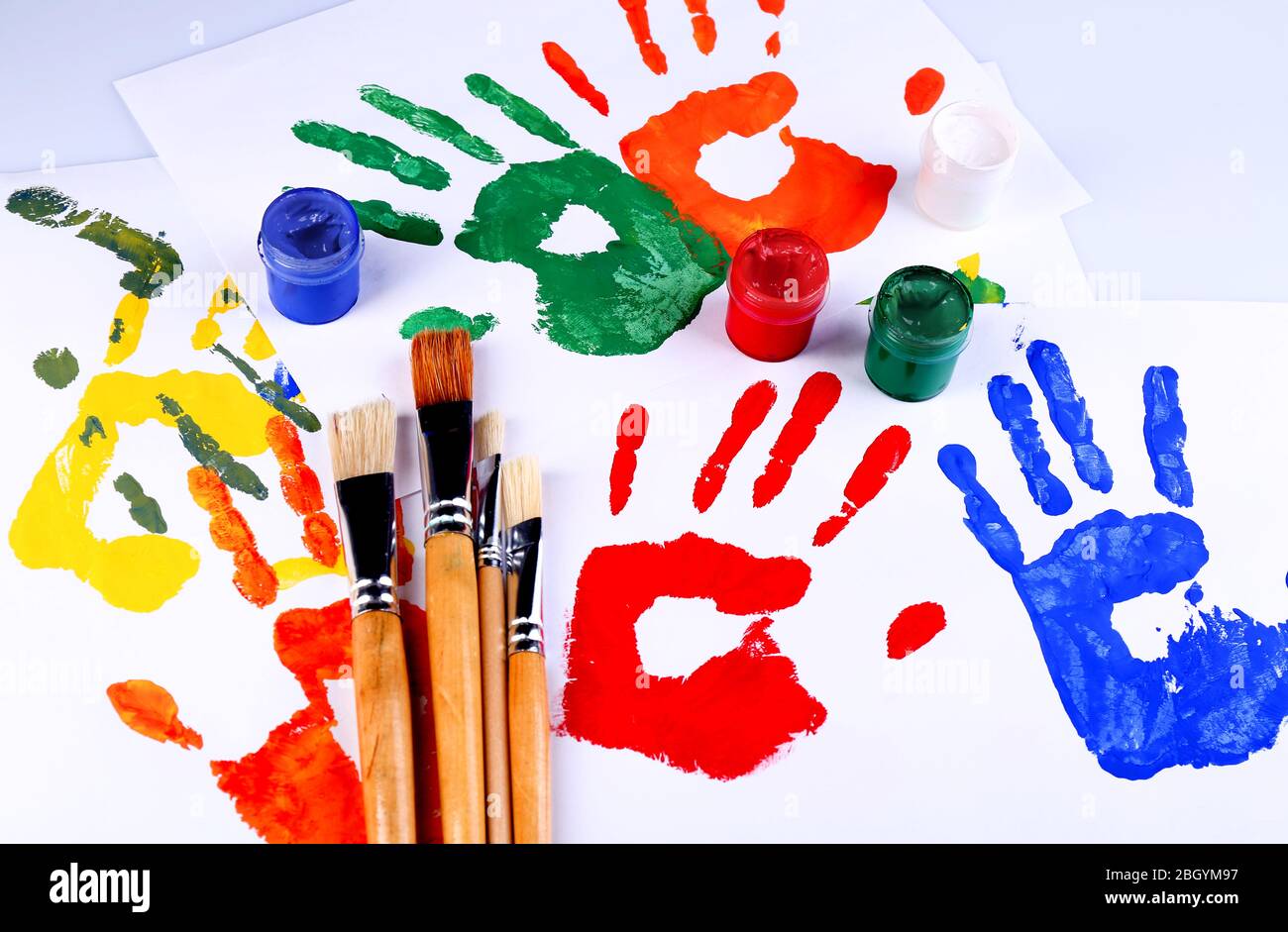 Hand prints of paint, paints and brushes on white background Stock ...