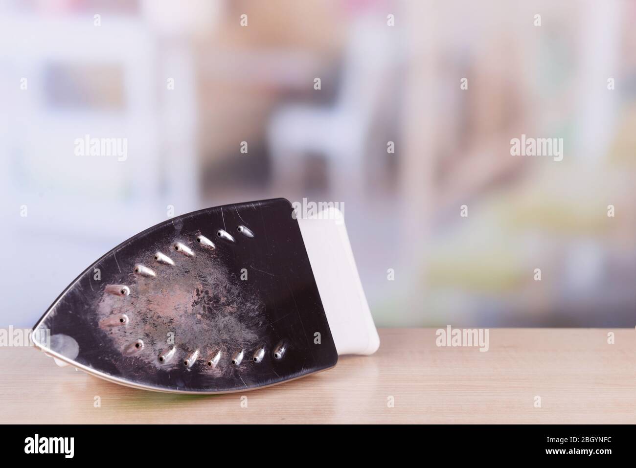 Flat iron with burnt mark on table on bright background Stock Photo - Alamy