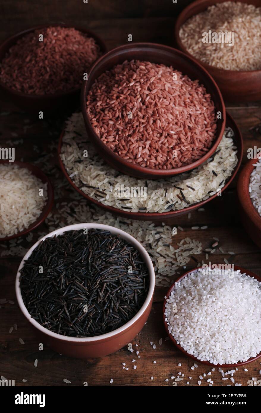 Different kinds of rice in bowls on wooden background Stock Photo - Alamy