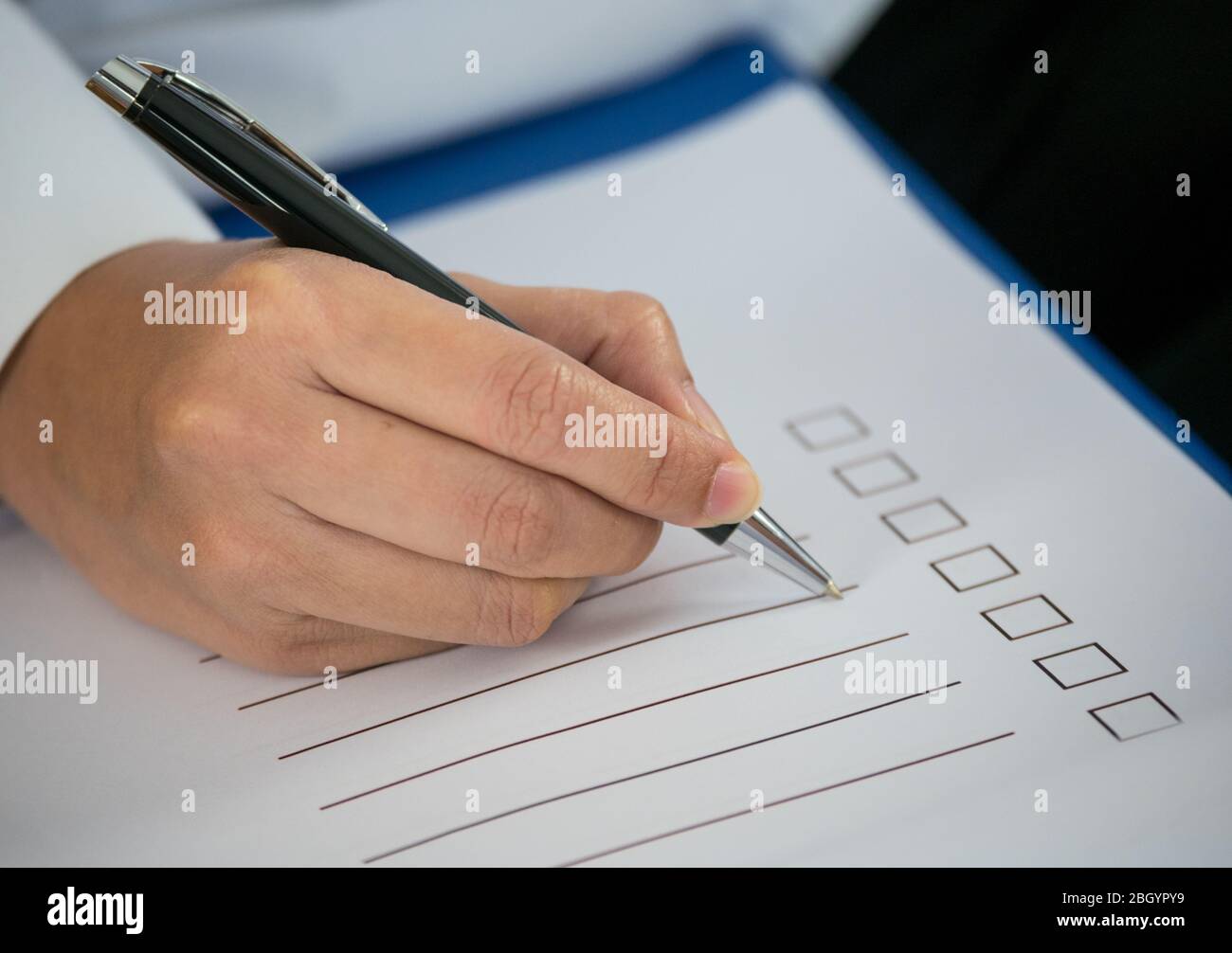 Close- up hand holding pen on check list paper and the format for ...