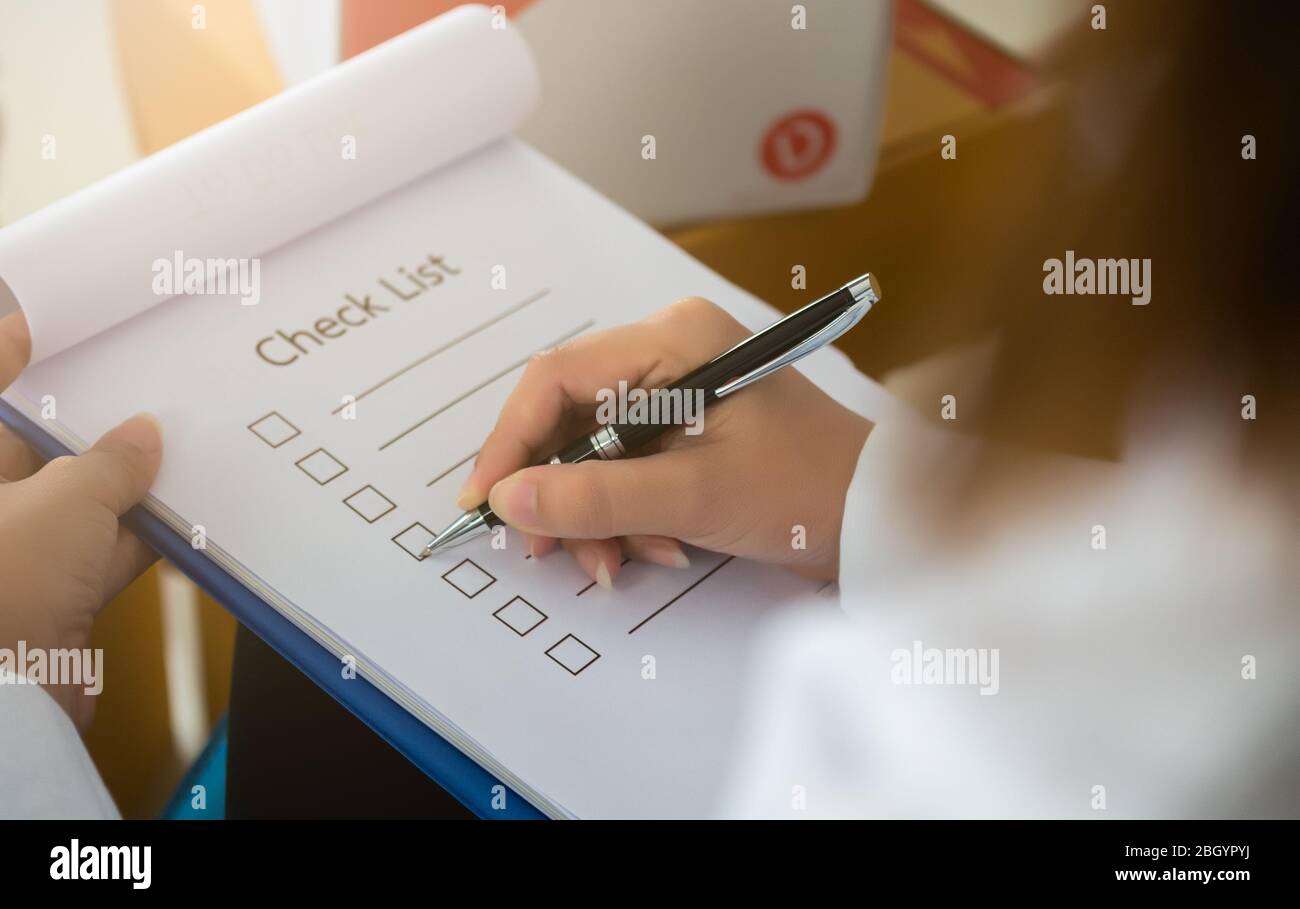 Close- up hand holding pen on check list paper and the format for ...