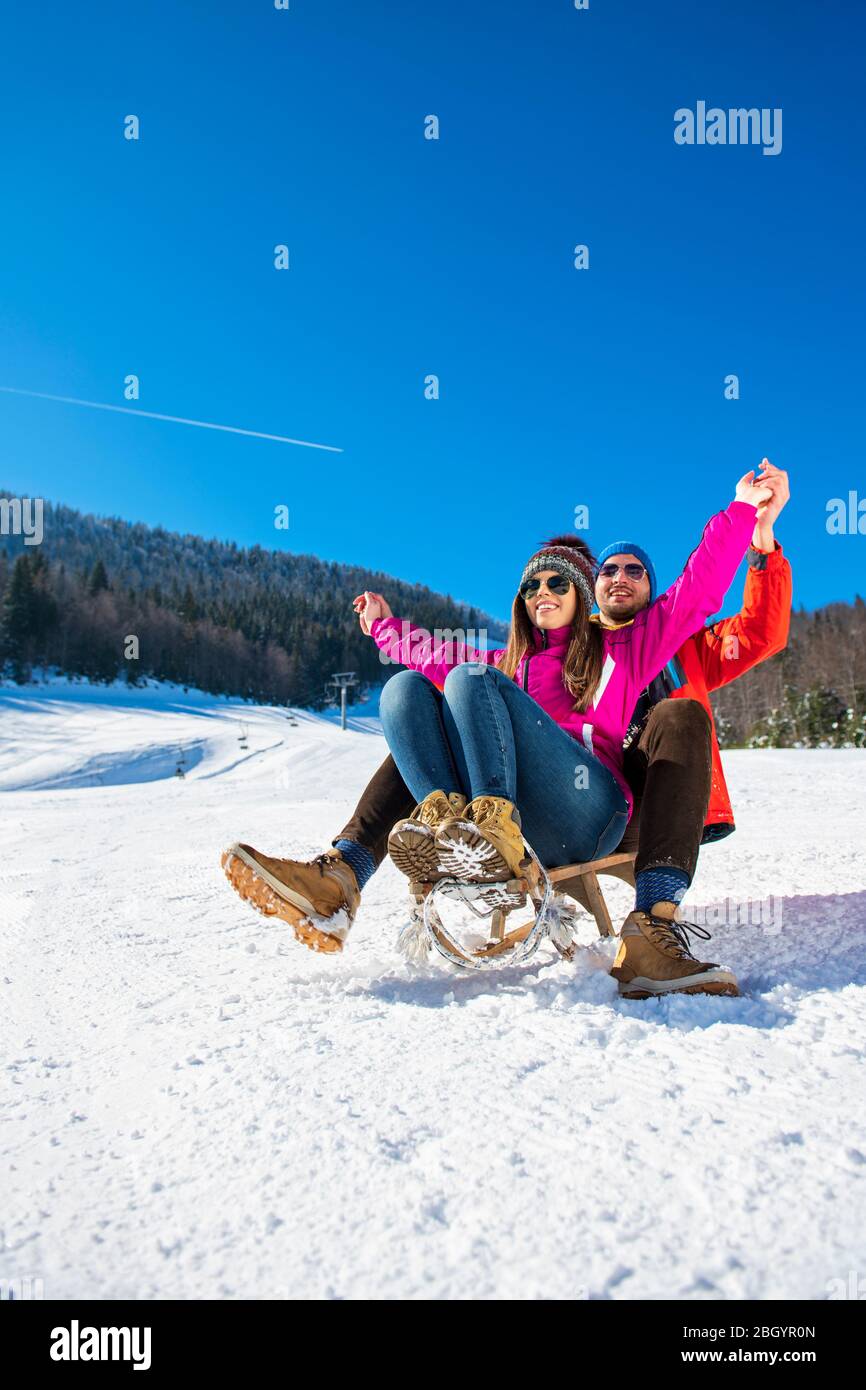 Young happy couple sledding in winter at ski center Stock Photo - Alamy