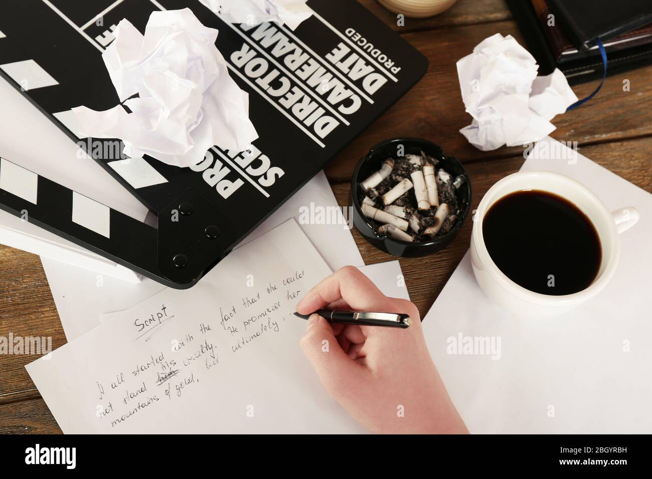 Female hand writing script at desktop with moving clapper and sheets of ...