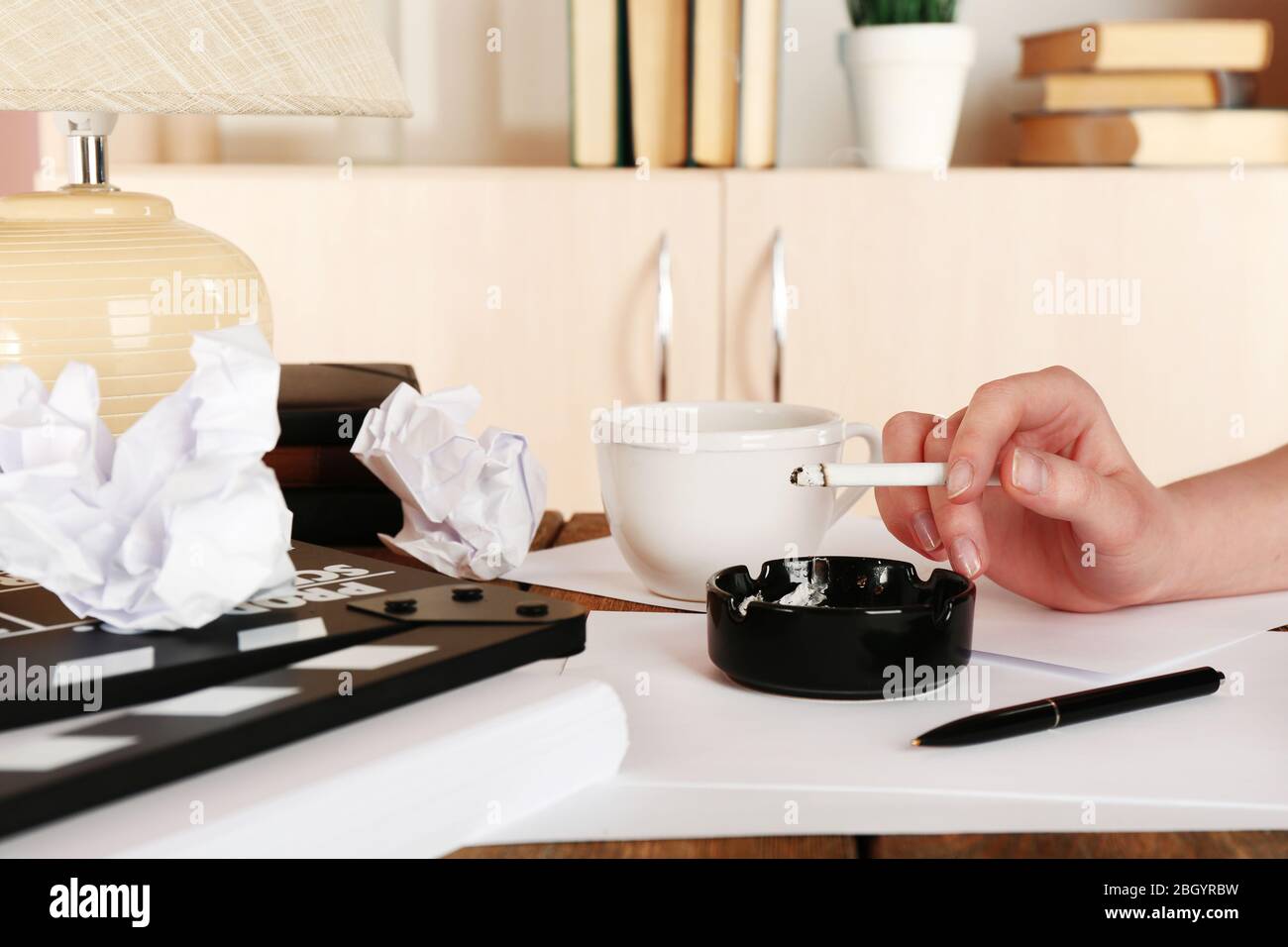 Female hand with cigarette at desktop with moving clapper and working ...
