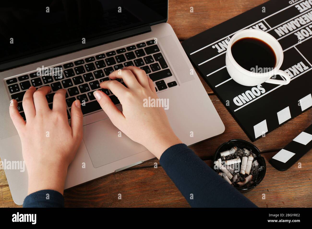 Female hands of scriptwriter working on laptop at wooden desk ...