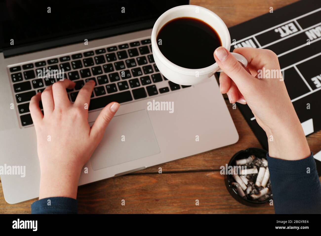 Female hands of scriptwriter working on laptop at wooden desk ...