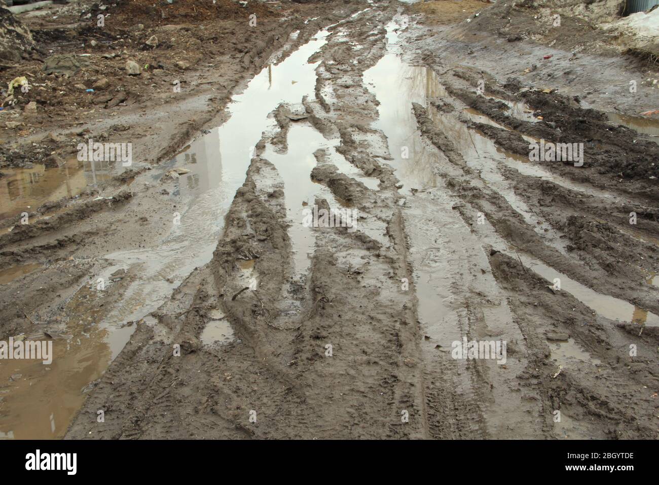 Dirty dirt road with track, wheel marks, brown clay and puddles in ...