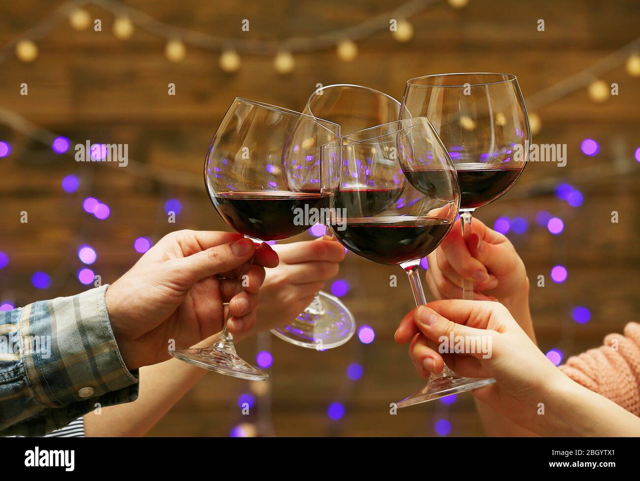 Clinking glasses of red wine in hands on bright lights background Stock ...
